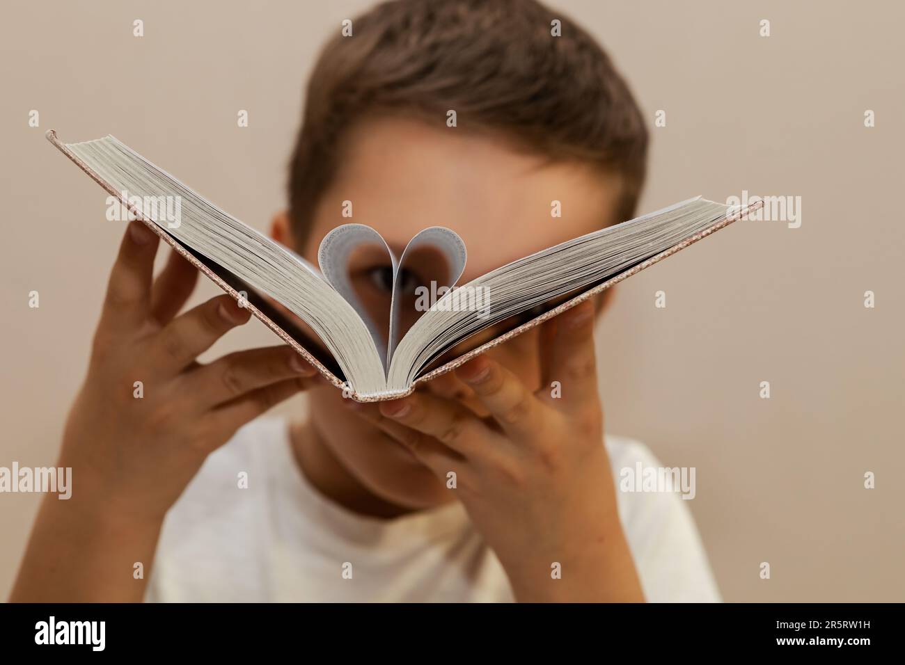 A 10-year-old boy has turned the pages of a book and looks through them ...