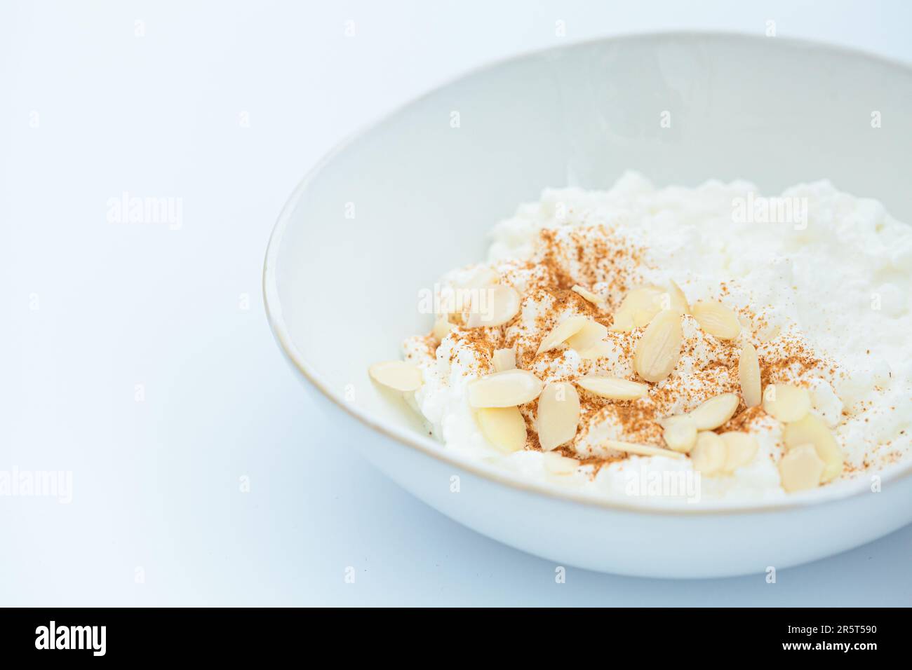 Cottage cheese with cinnamon and almonds in a white bowl, white ...