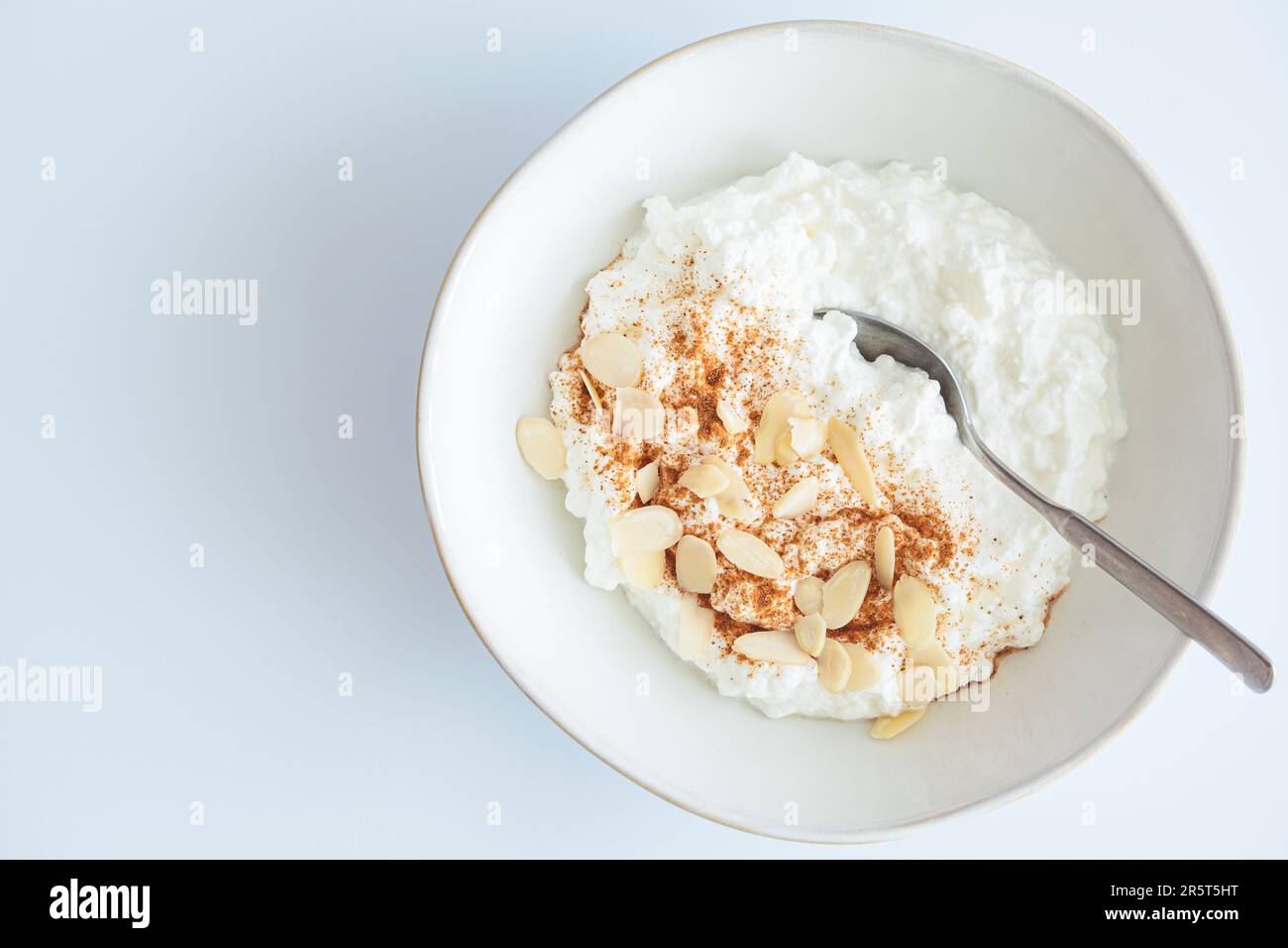 Cottage cheese with cinnamon and almonds in a white bowl, white ...