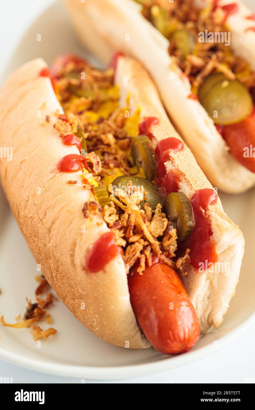 Classic hot dog with mustard, ketchup, pickles and fried onions, white ...