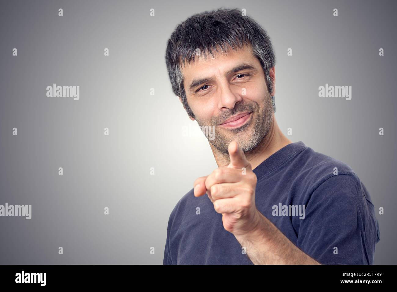 Smiling middle-aged man pointing with index finger over gray background. Success concept Stock ...