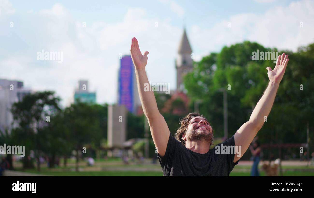 Faithful young man raises arms to sky feeling GRATEFUL standing ...