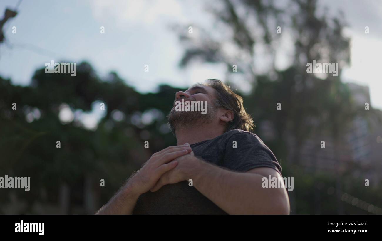 Mindful young man standing outdoors celebrates success. Contemplative ...