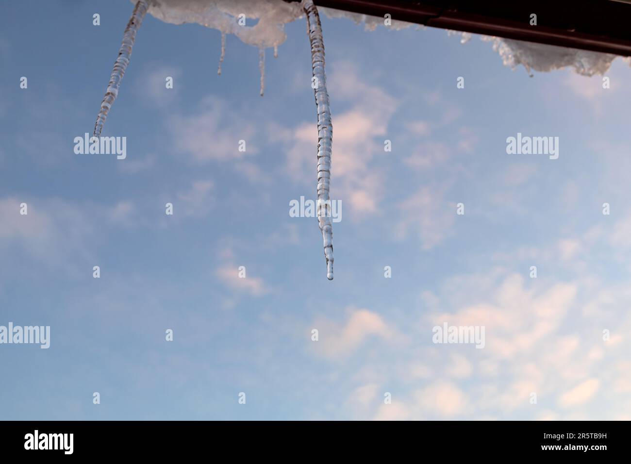 icicles hanging from the edge of the roof dripping water Stock Photo ...