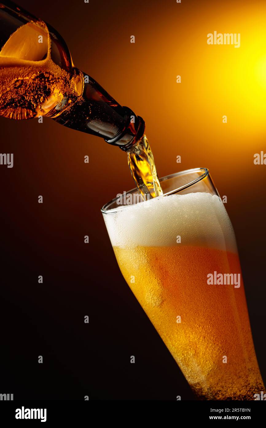 Pouring beer from a bottle into a tall glass Stock Photo - Alamy