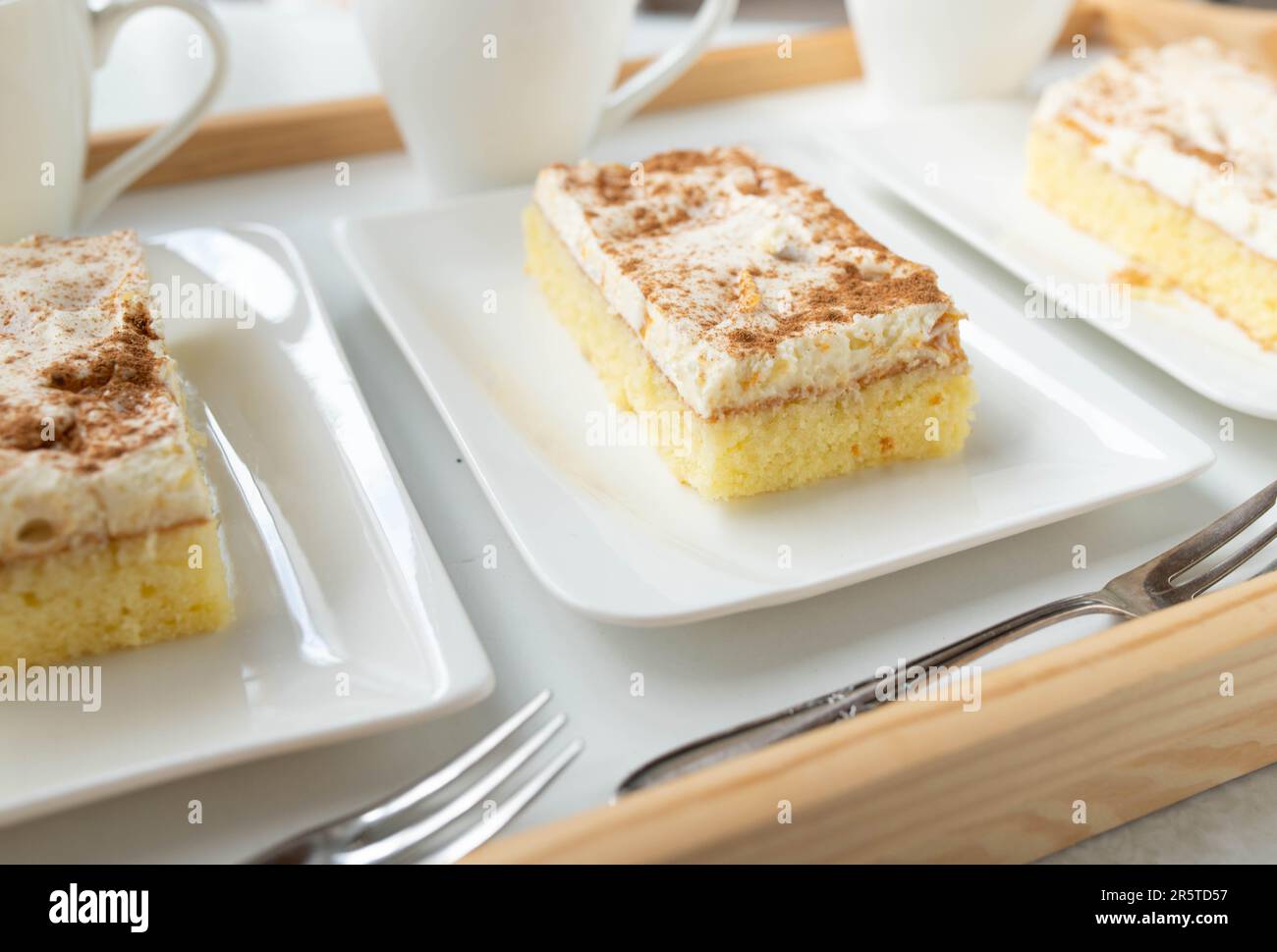 Sponge cake with sour cream, tangerine, cinnamon topping on plates ...