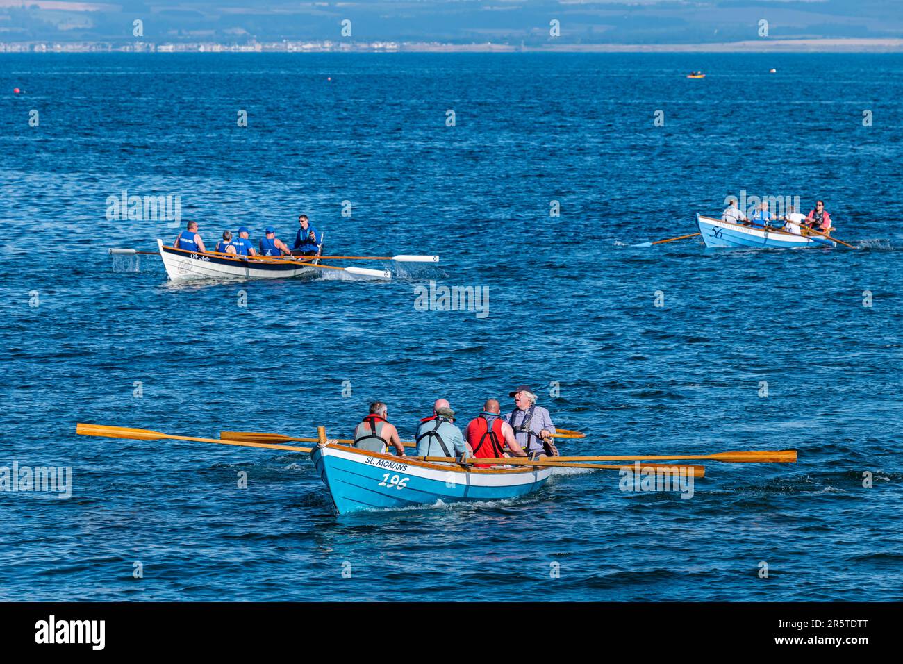 Crews rowing in St Ayles' skiffs boats in coastal rowing regatta in sunny weather, Firth of ...