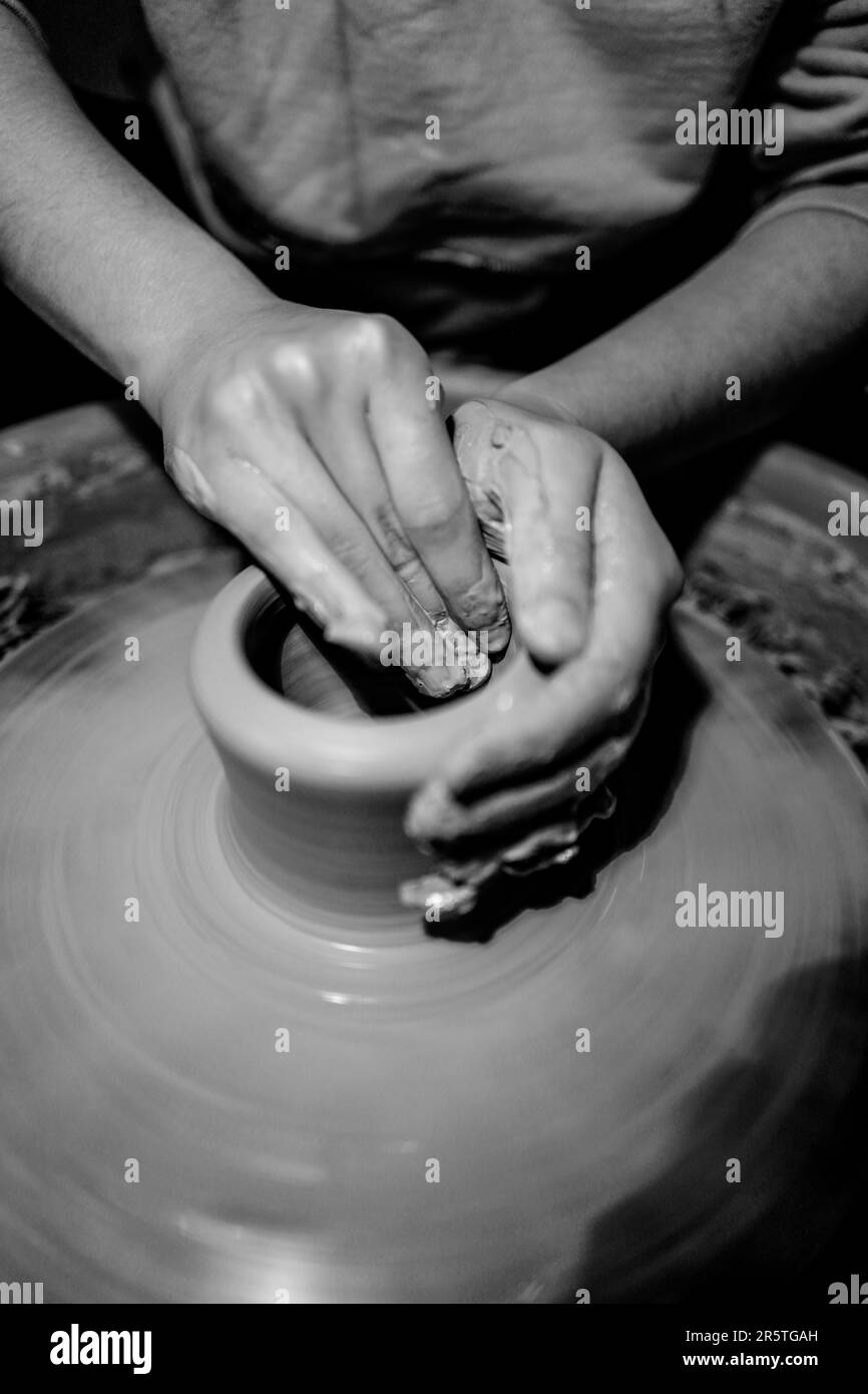 A black and white image of a person using a pottery wheel to create a ...