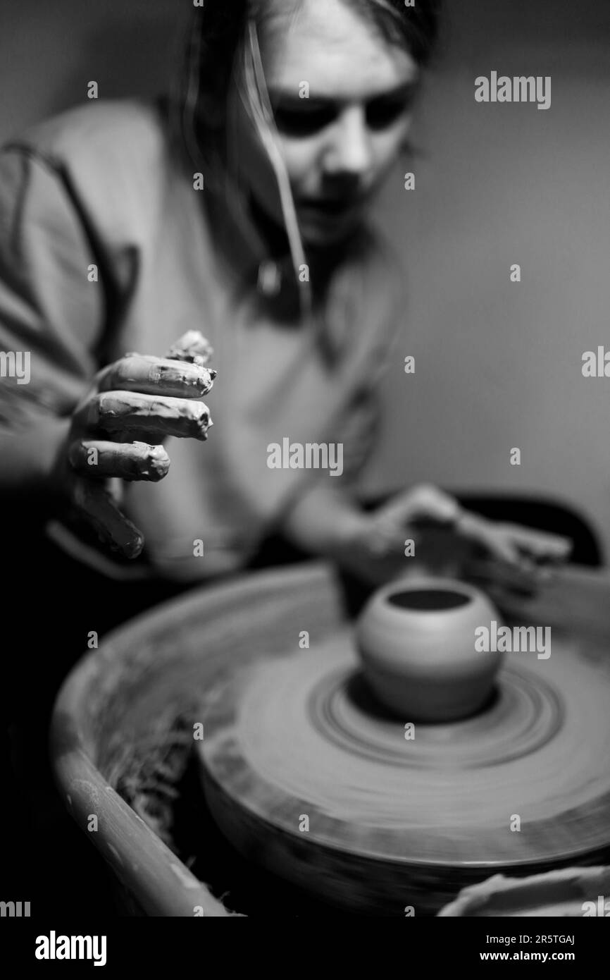 A female artisan sits at a work table in a cozy home studio, skillfully ...