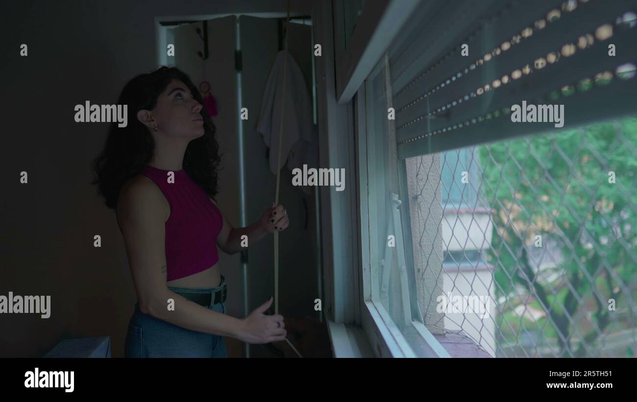 Woman shutting window blinds at home. Person turning room pitch dark ...