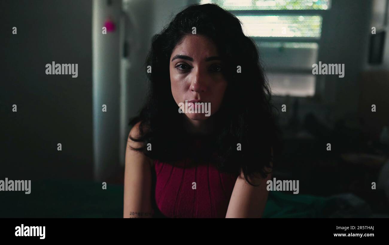 One young woman with serious expression portrait face closeup looking at camera inside a dark ...