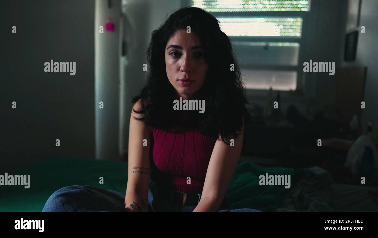 One young woman with serious expression portrait face closeup looking at camera inside a dark ...