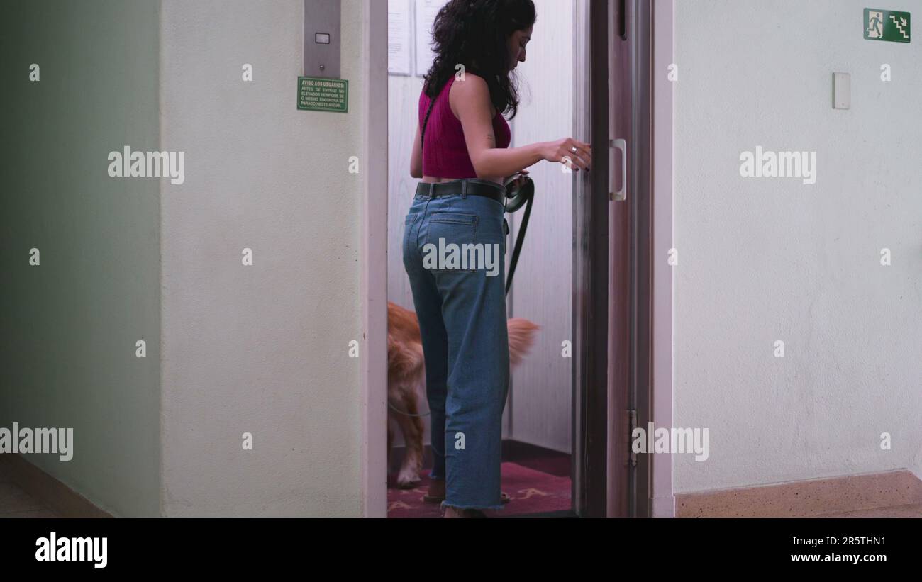 Woman opening elevator door going for a walk with her Dog on a leash ...