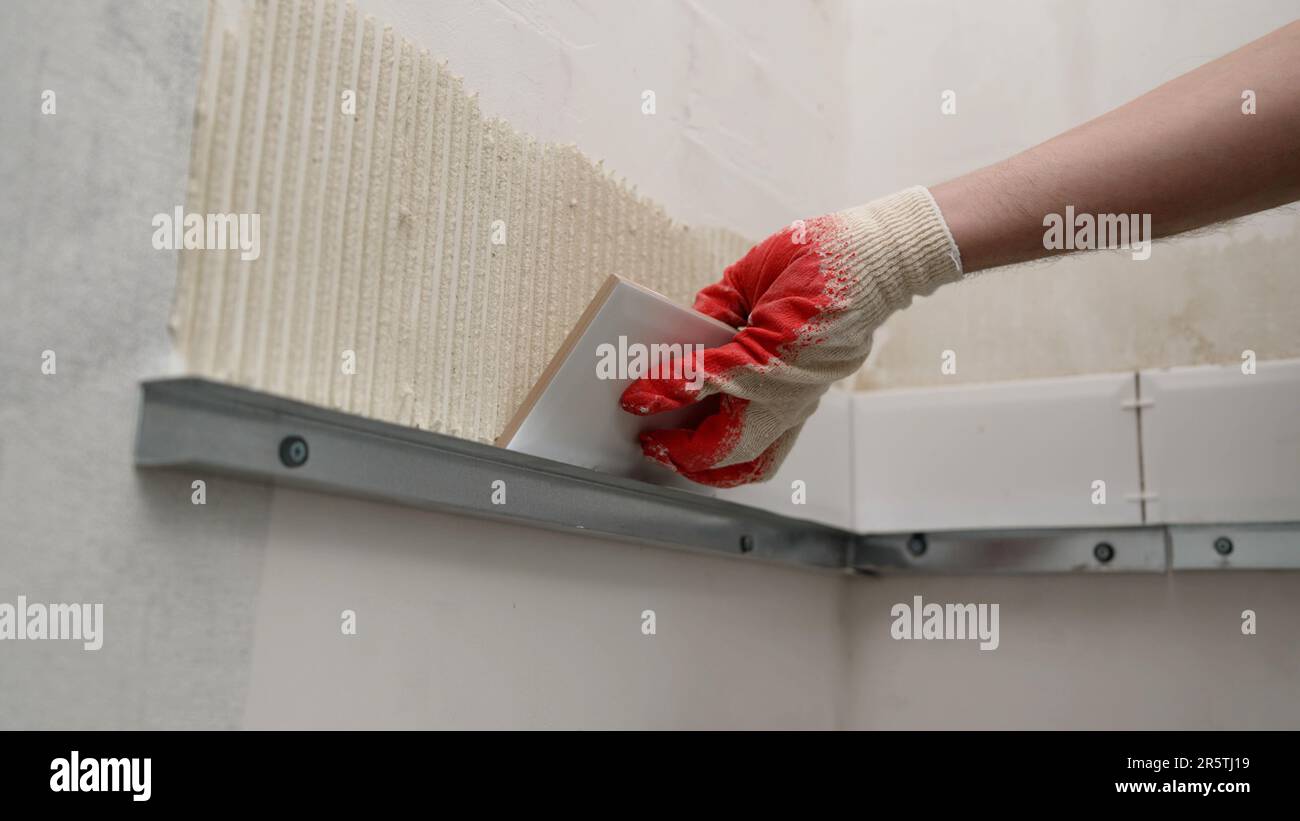 Industrial close-up of a worker's hand applying cement adhesive for ...
