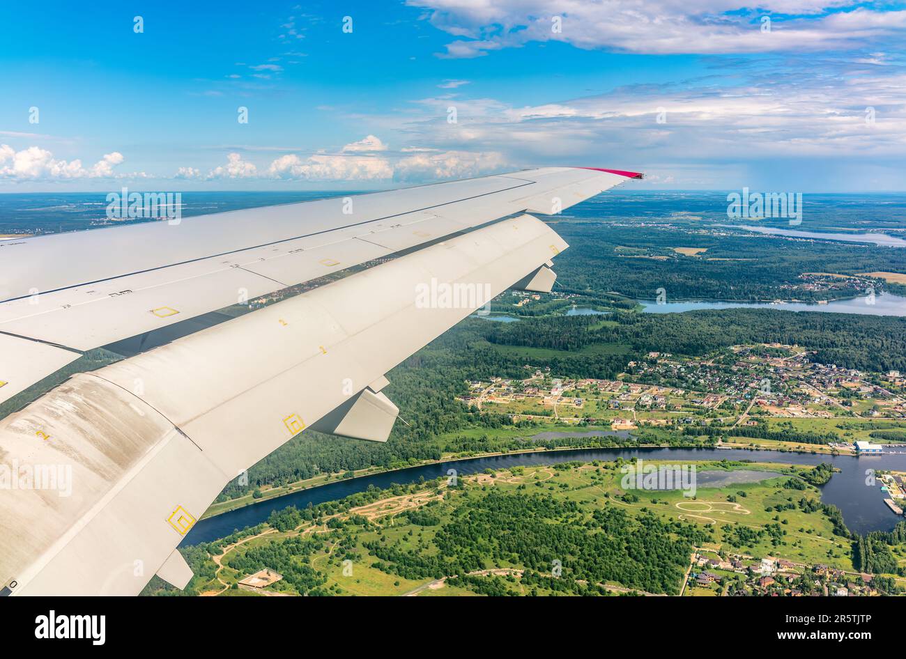View of airplane wing, blue skies and green land during landing ...