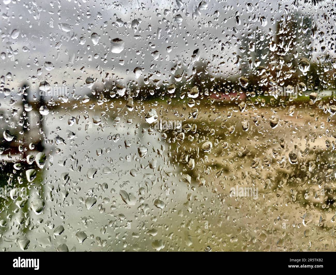 A close up photograph of raindrops on a glass window, with a background ...
