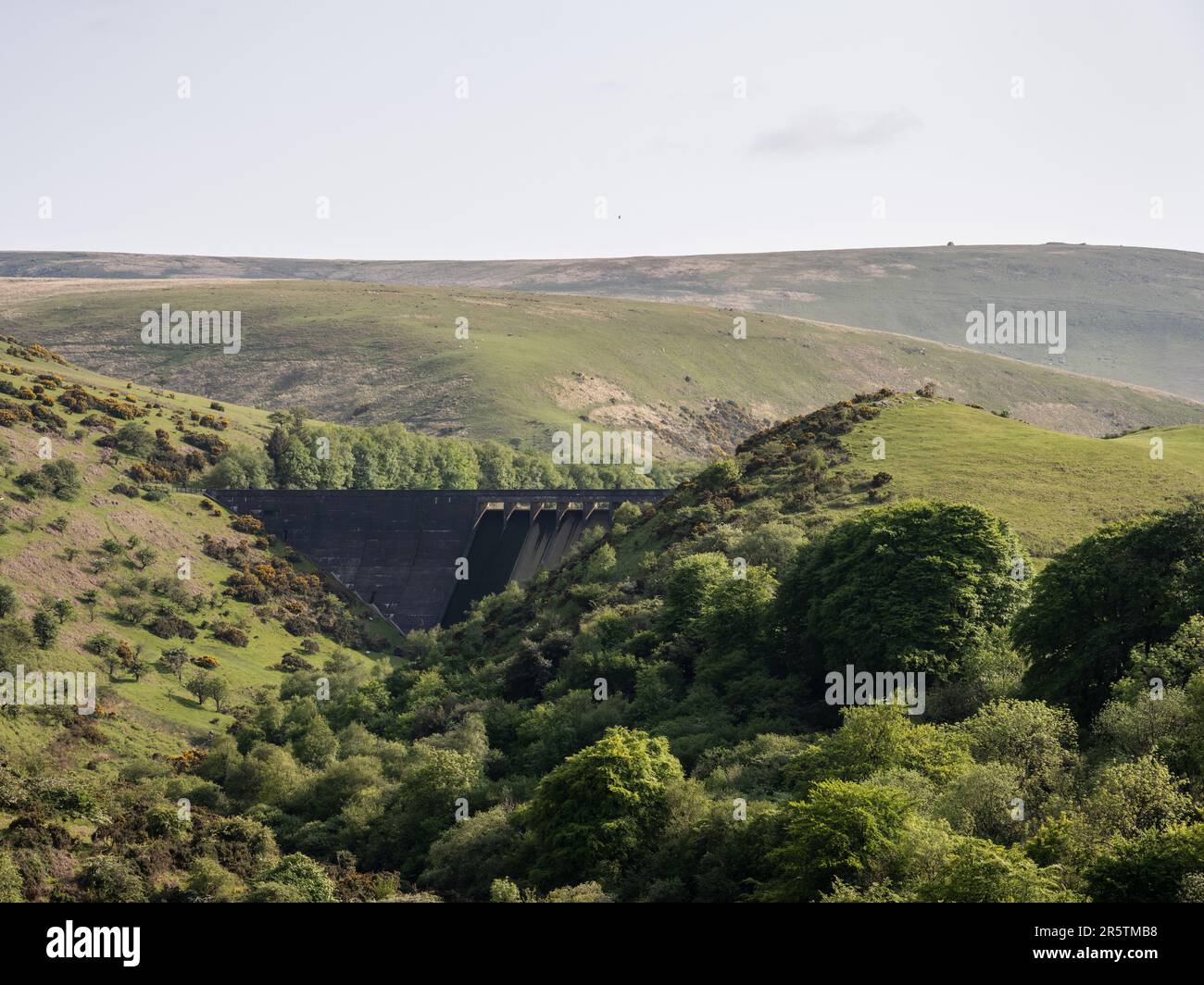 The concrete dam of Meldon Reservoir in a valley under the hills of ...