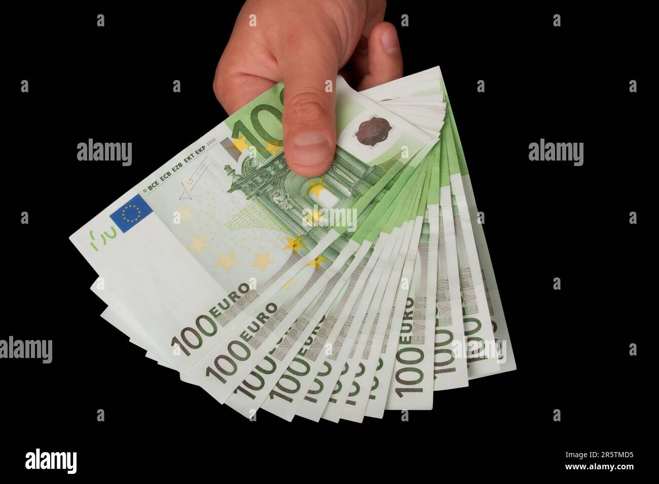 A person's hand grasping a pile of cash dollars, symbolizing financial ...