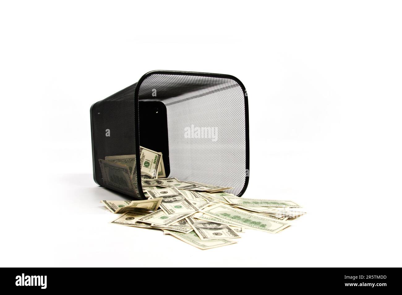 An empty trash can overflowing with crisp one hundred dollar bills ...