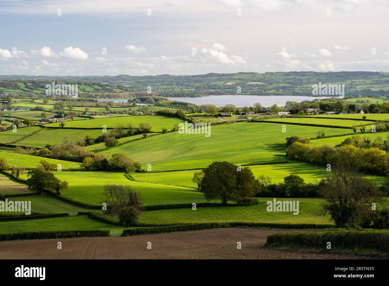 Sun shines on green fields and reservoir of the Chew Valley in North ...