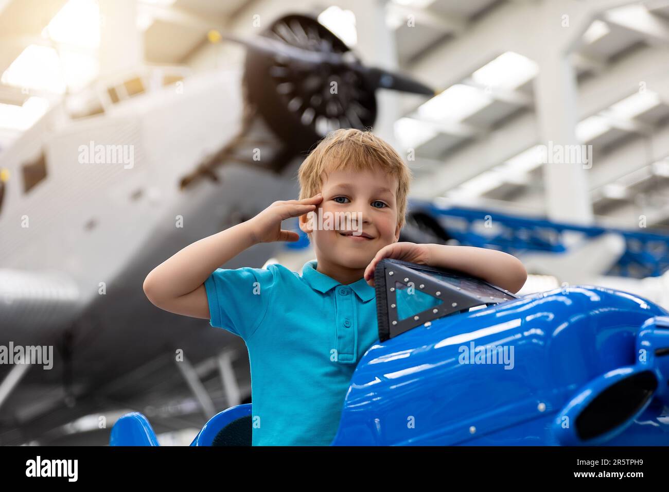 Portrait of cute little blond happy kid boy enjoy have fun play riding ...