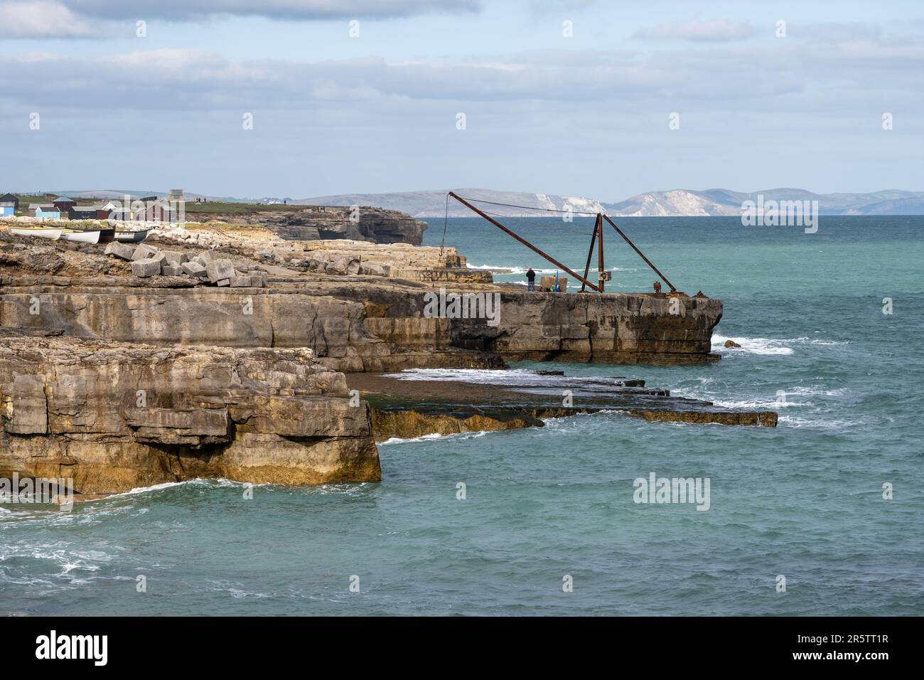 A fisherman stands beneath a traditional quarry crane beside the ...