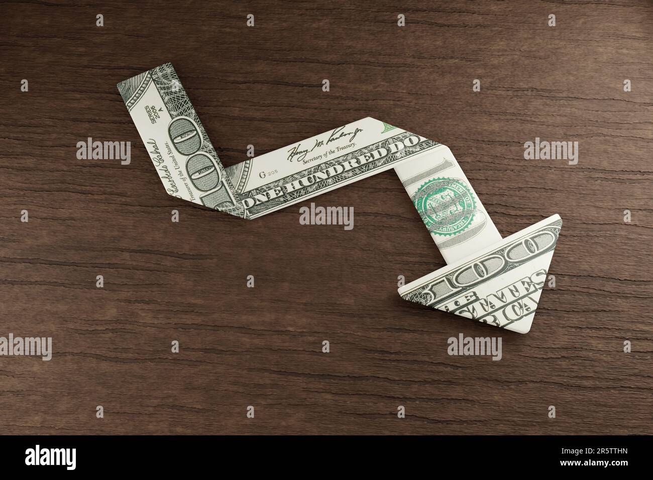 US 100 dollar bills folded into a downward trend arrow of chart ...