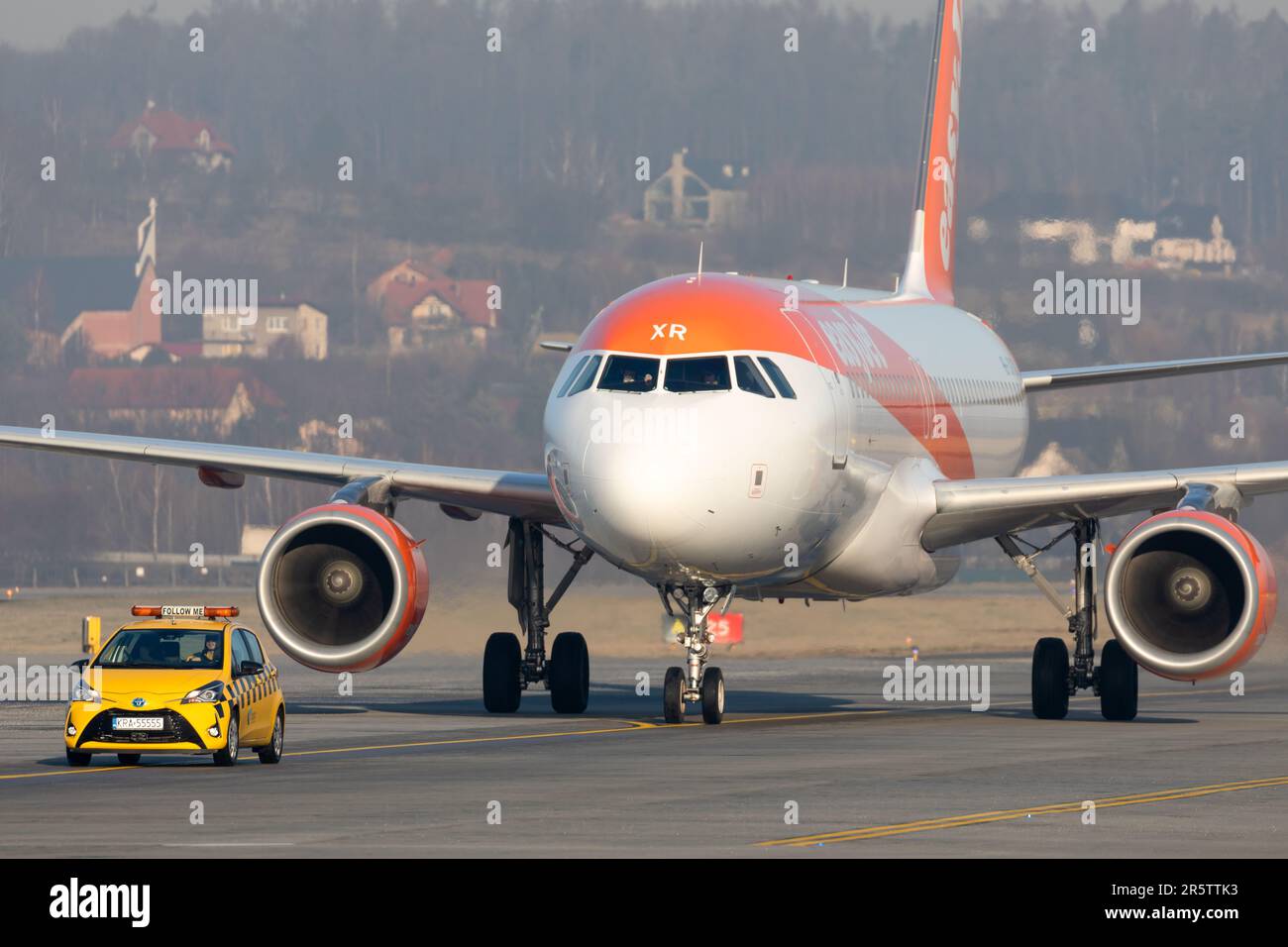 An orange and white single engine jet is parked on a runway next to a ...