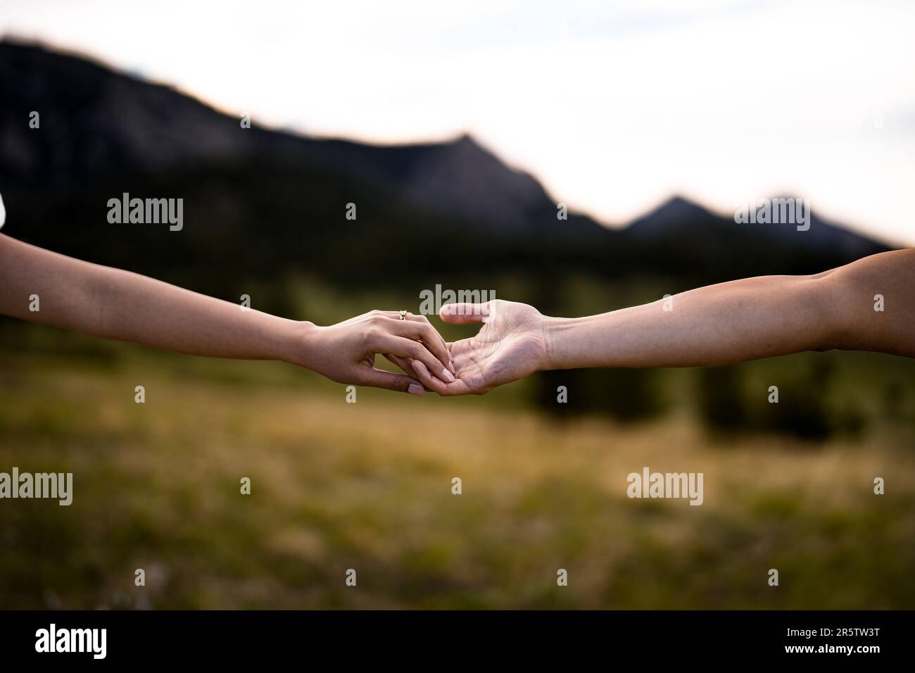 Two people in an embrace, hands touching in a display of affection ...