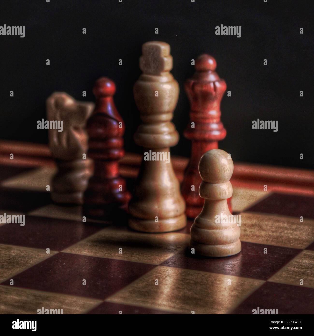 Four wooden chess pieces are positioned side by side on a classic ...