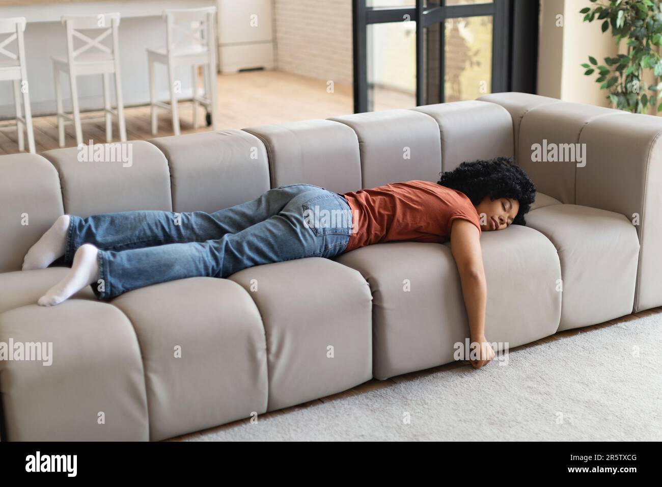 Tired young black woman sleeping on couch during day, feeling exhausted ...