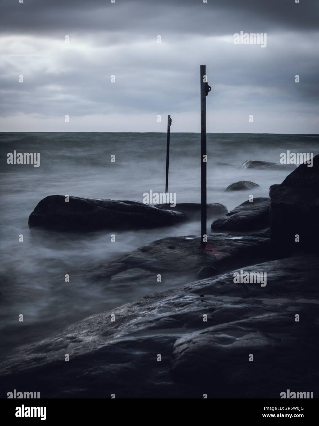 A single wooden pole extending out of the deep blue ocean in front of a ...