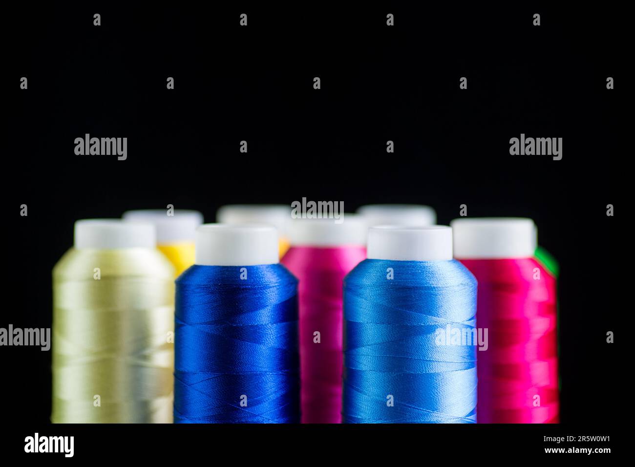 set of different color sewing threads, isolated on black background ...
