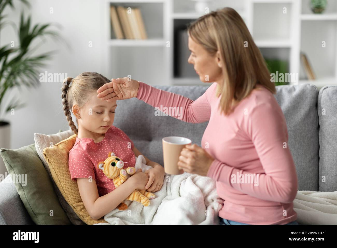 Caring Mother Giving Tea To Ill Little Daughter And Touching Her ...