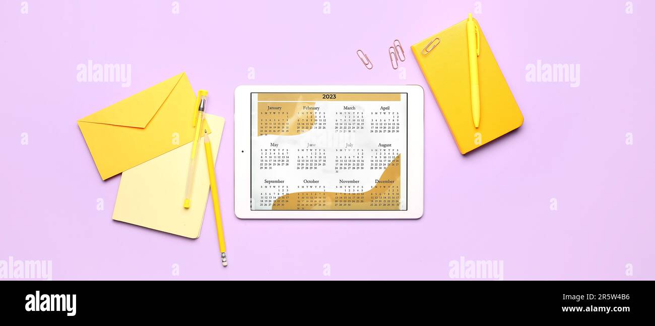 Calendar for 2023 year on screen of tablet computer and yellow office ...