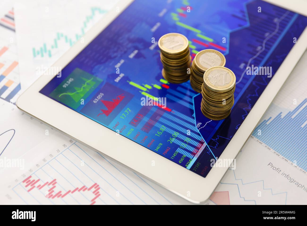 Coins and tablet computer with diagrams of exchange rates, closeup ...
