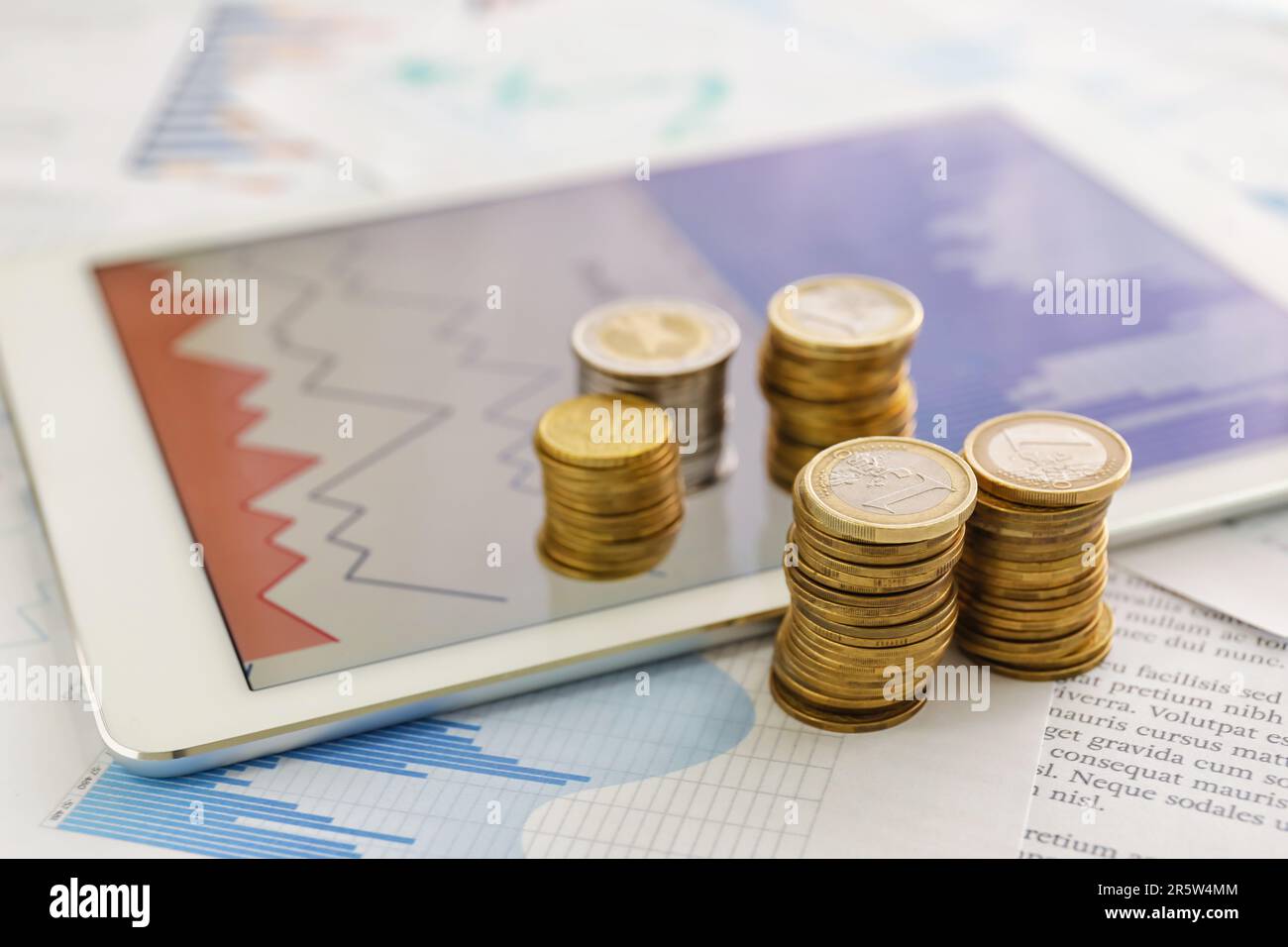 Coins and tablet computer with diagrams of exchange rates, closeup ...