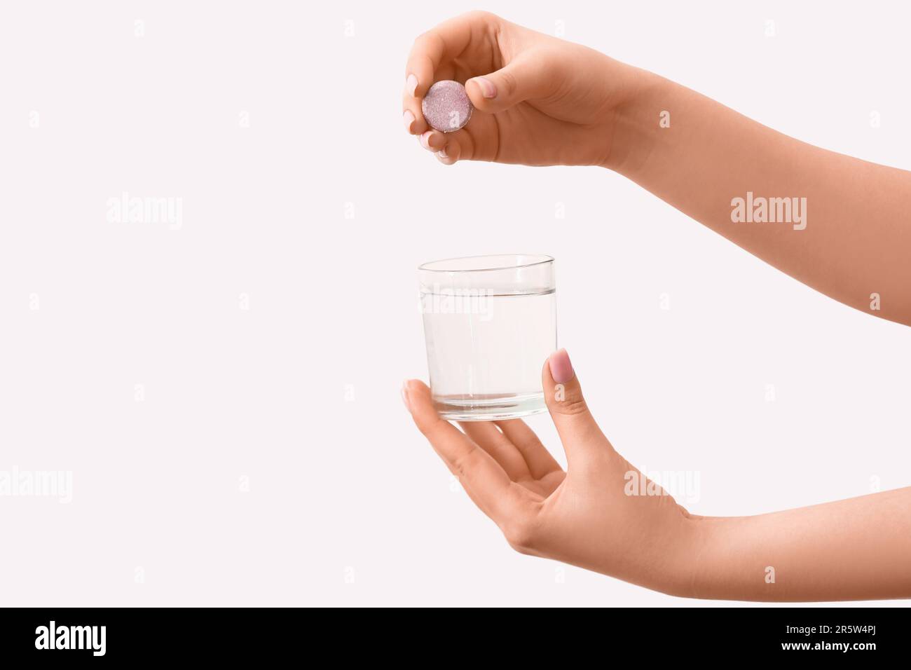 Woman putting soluble tablet into glass of water on white background ...