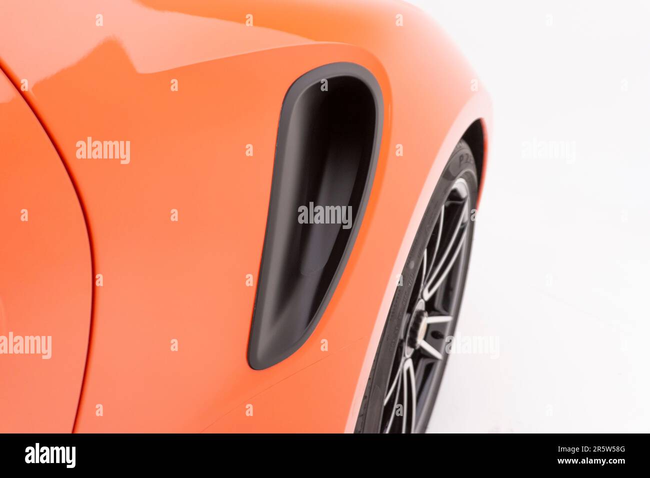 The front wheel of an orange Porsche car, showing the chrome rim and ...