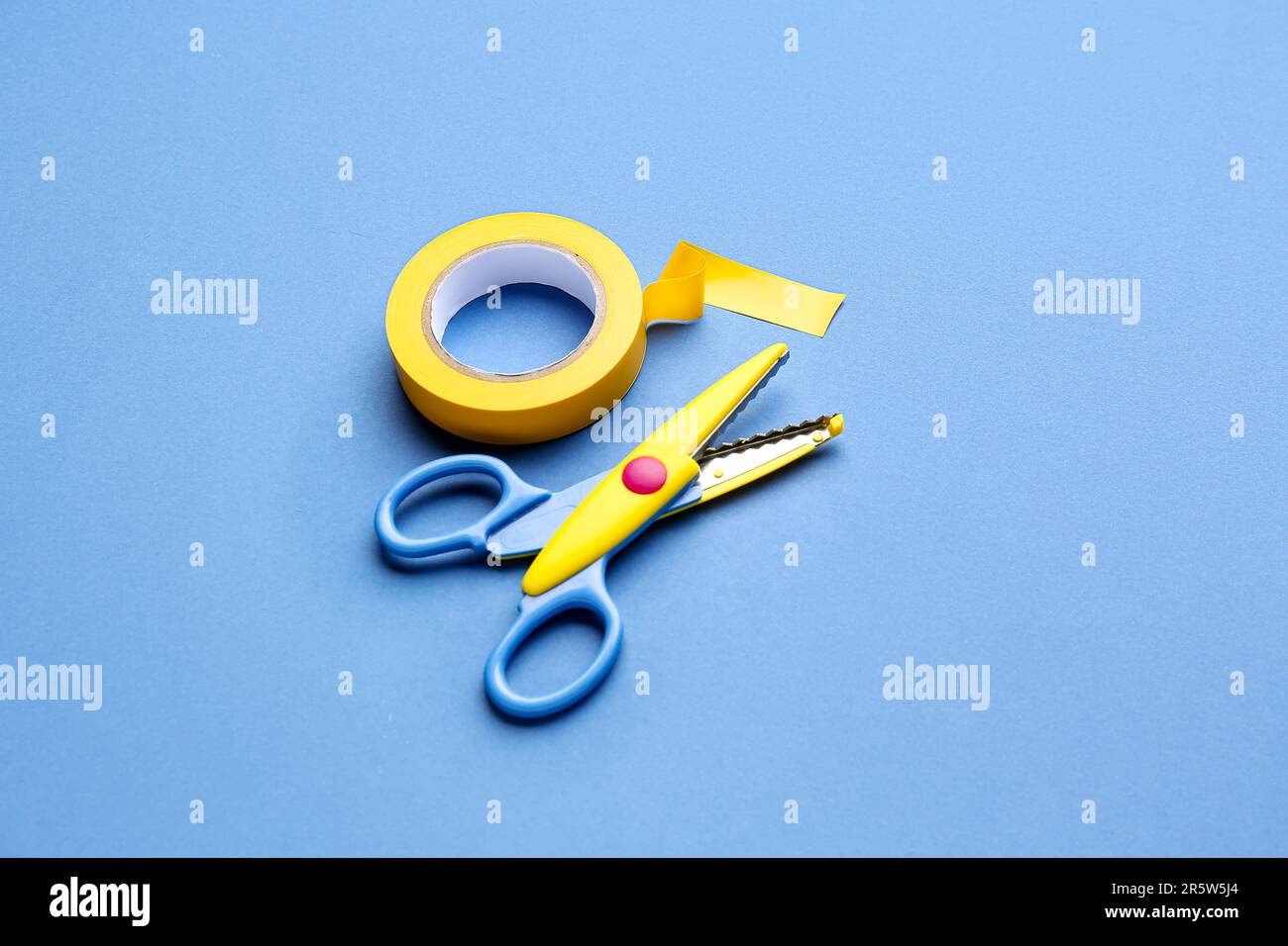 Adhesive tape roll and stationery scissors on blue background Stock ...