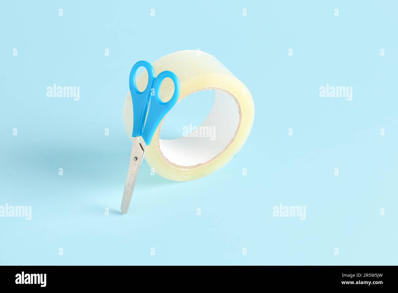 Adhesive tape roll and stationery scissors on blue background Stock ...
