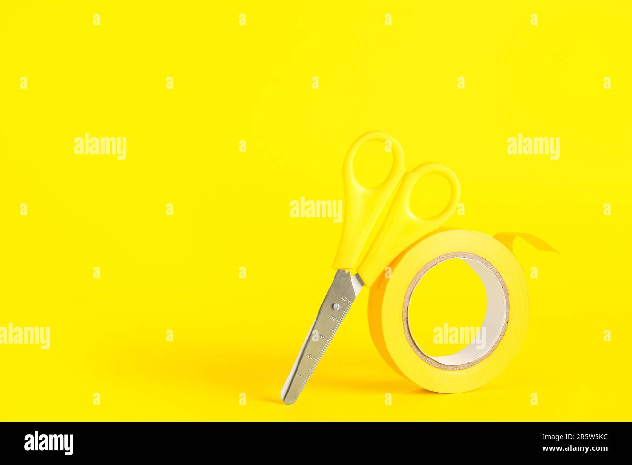Adhesive tape roll and stationery scissors on yellow background Stock ...