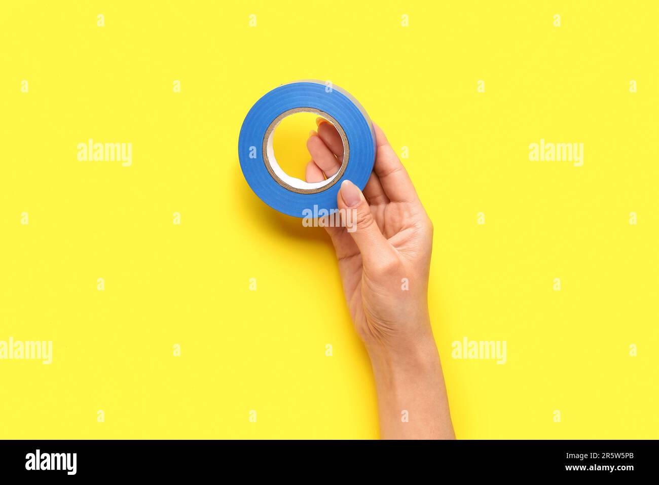 Female hand holding adhesive tape roll on yellow background Stock Photo ...
