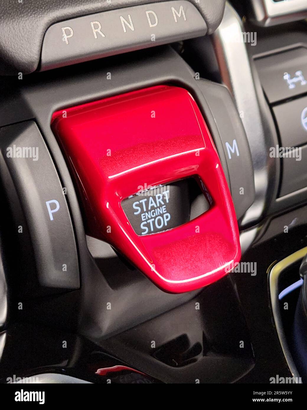 A closeup of a red car dashboard featuring a button for controlling the ...