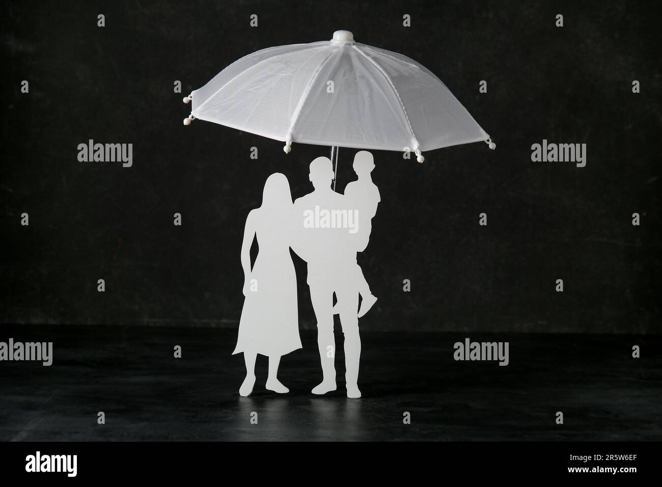 Creative composition with umbrella and paper humans figures on black ...