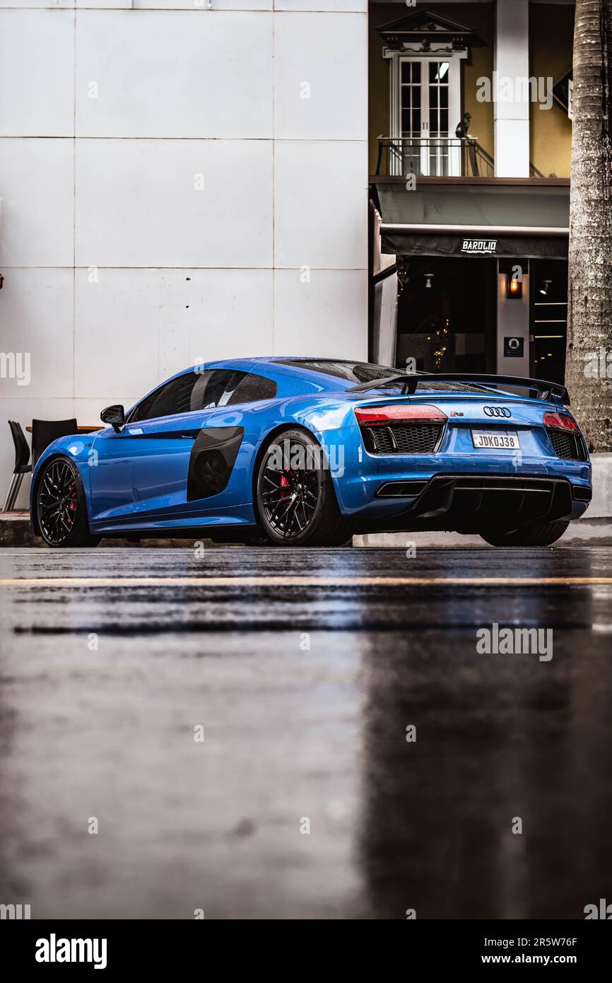 A blue four-door audi car parked in front of a modern high-rise ...