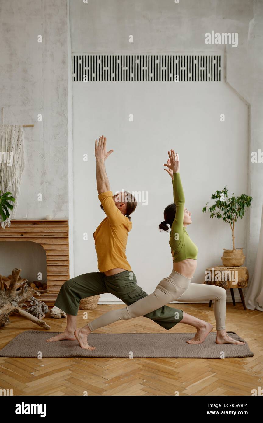 Young man and woman couple practicing yoga together standing in ...