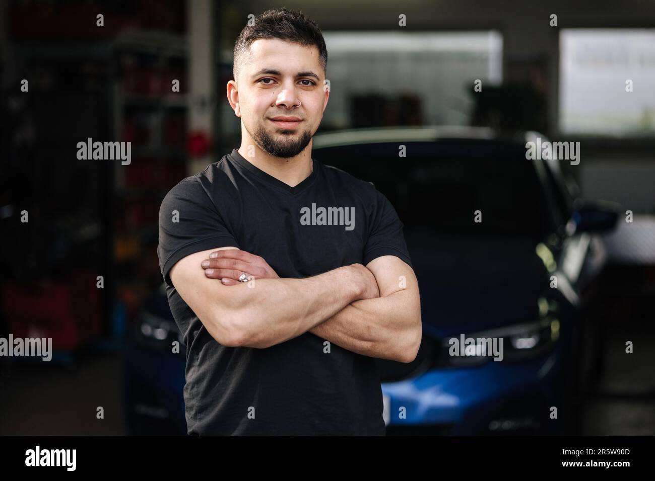 Portrait of handsome male owner of car repair shop. Bearded mechanic at ...