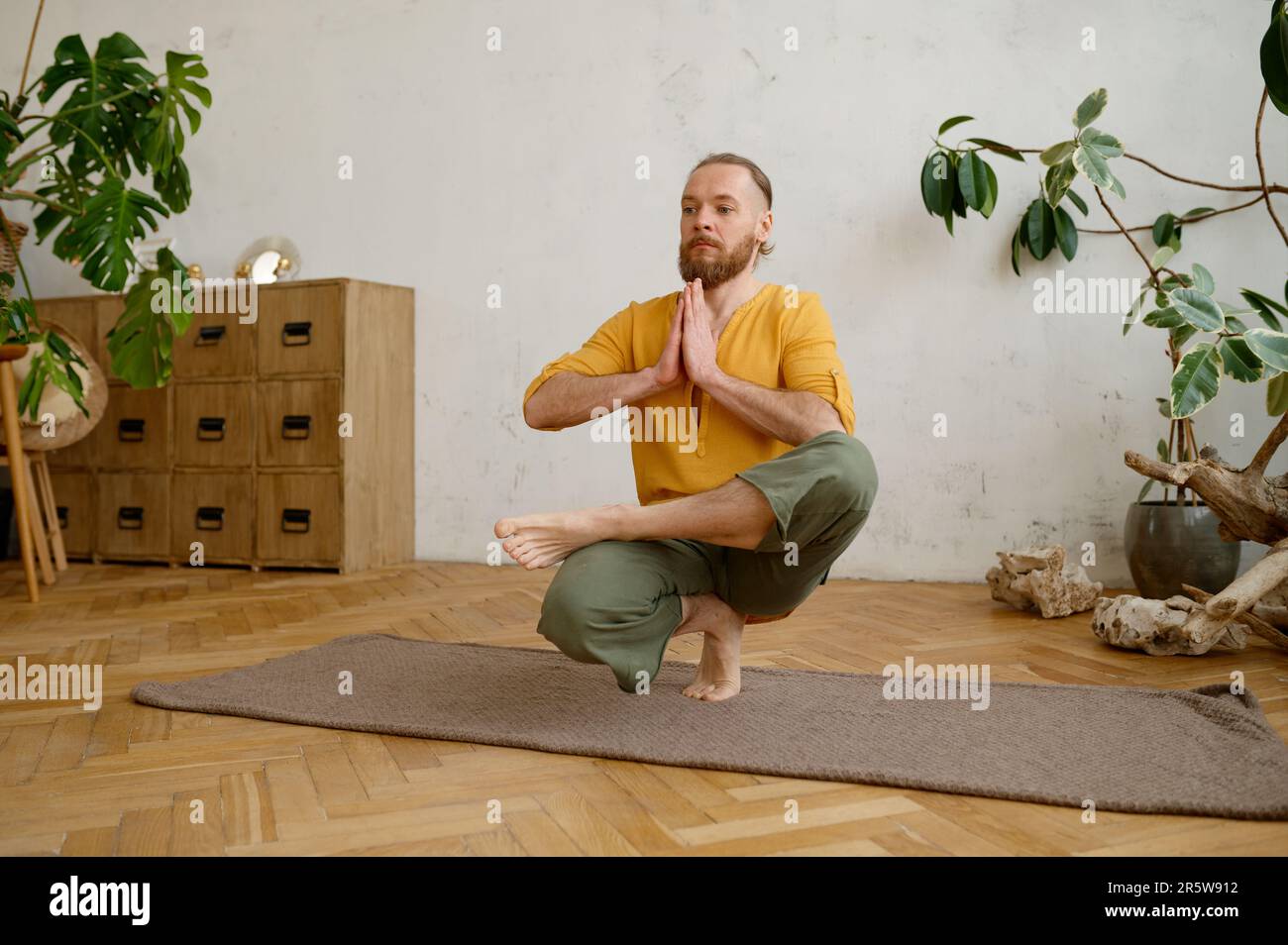 Strong fit man balancing on one leg in squatting position Stock Photo ...