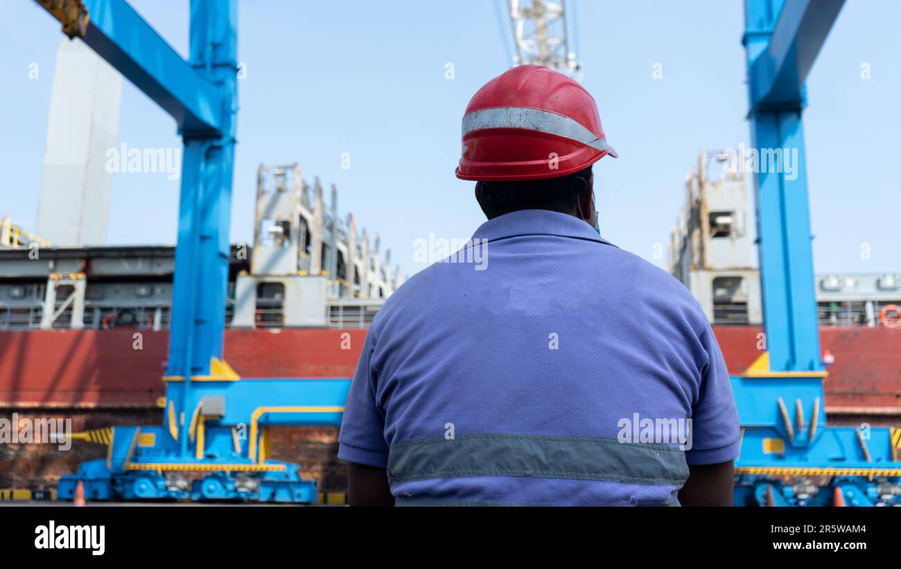 Latino worker seen from behind maritime logistics at a cargo port Stock ...
